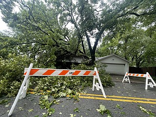 A tree sits on a house Tuesday July 9, 2024  on Evergreen Street near the Tyler Street intersection in Little Rock following Monday night’s storms. (Arkansas Democrat-Gazette/Thomas Metthe).