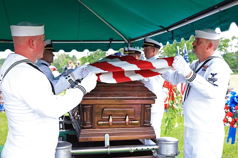Honor guard members fold an American flag over the casket of Arkansas ...