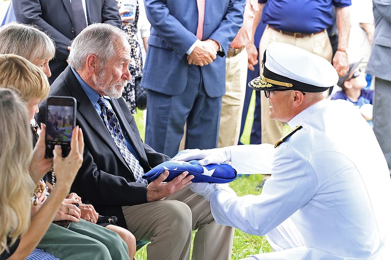 Rear Admiral Michael VanPoots (right) presents a folded American flag ...