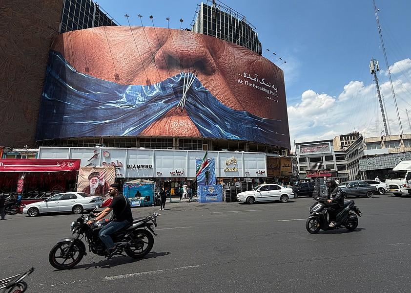 AP Photo by Vahid Salemi / Vehicles drive past a billboard with graphic ...