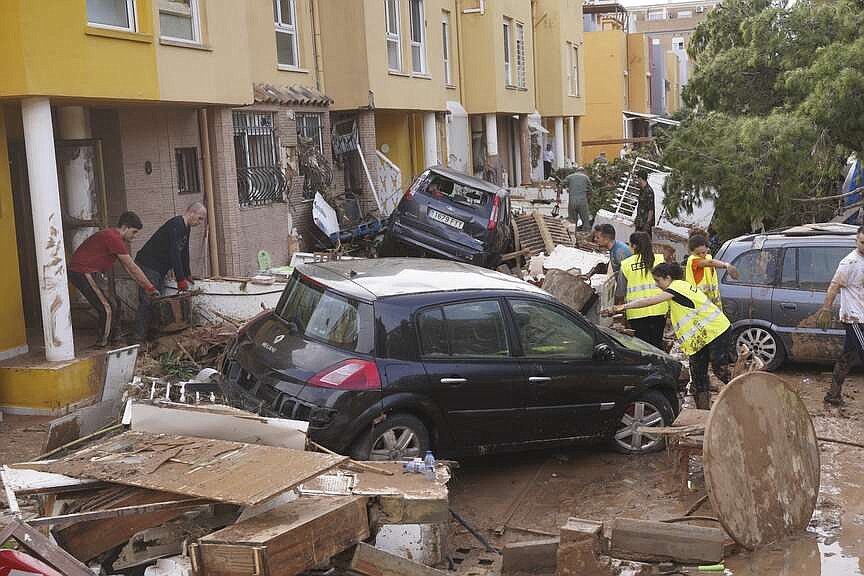 Muddy volunteers clean flood debris in Spanish town as authorities ...