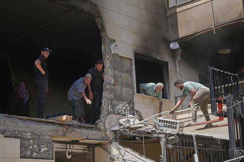 Residents and workers clear debris from an apartment building damaged ...